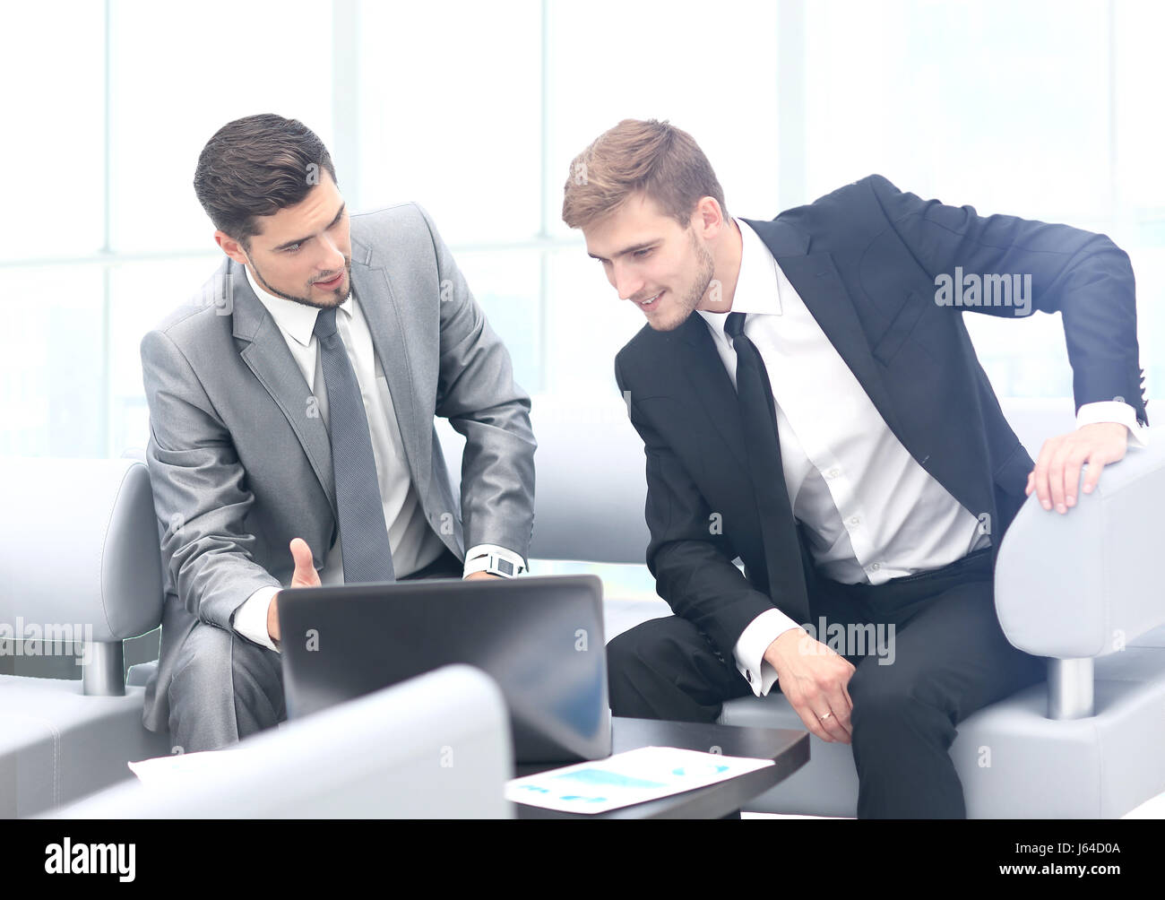 Smiling business men showing something on computer as colleague looking ...