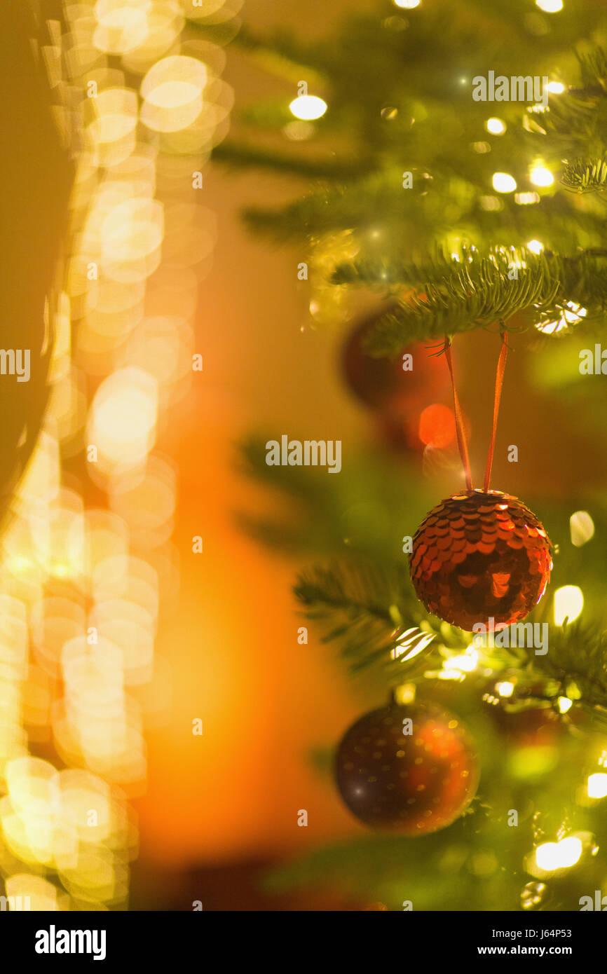 Red glitter ornaments hanging from Christmas tree with string lights ...