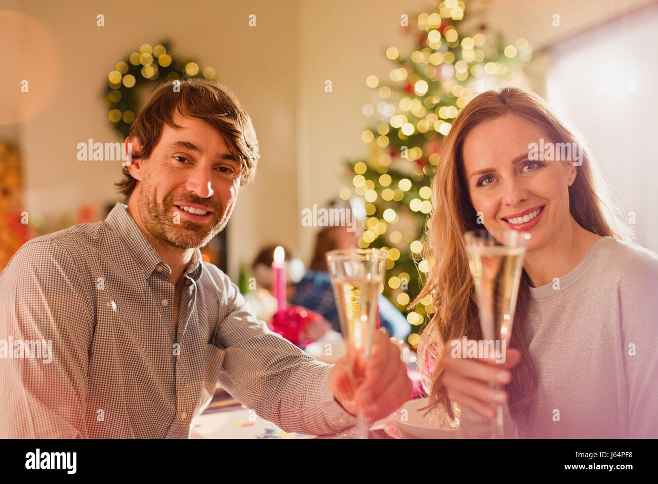 Portrait smiling couple toasting champagne flutes at Christmas dinner ...