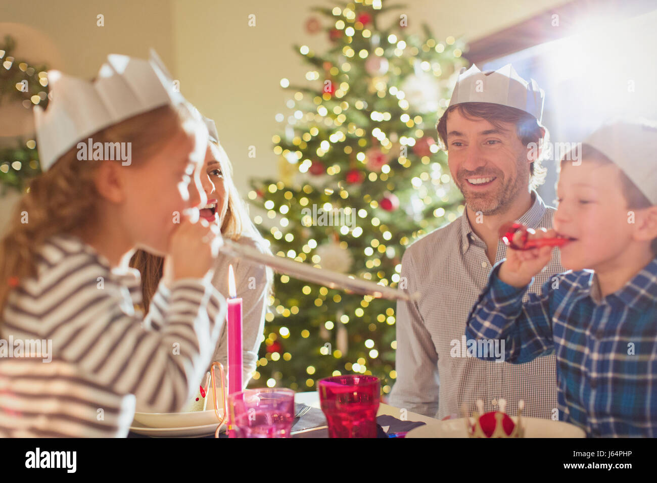 Family wearing paper crowns at Christmas dinner table Stock Photo - Alamy