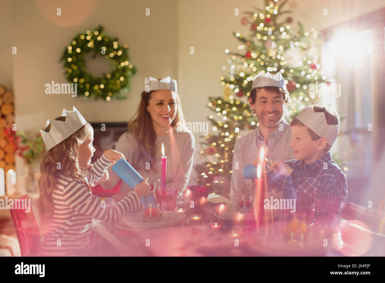 Family wearing paper crowns at Christmas dinner table Stock Photo - Alamy