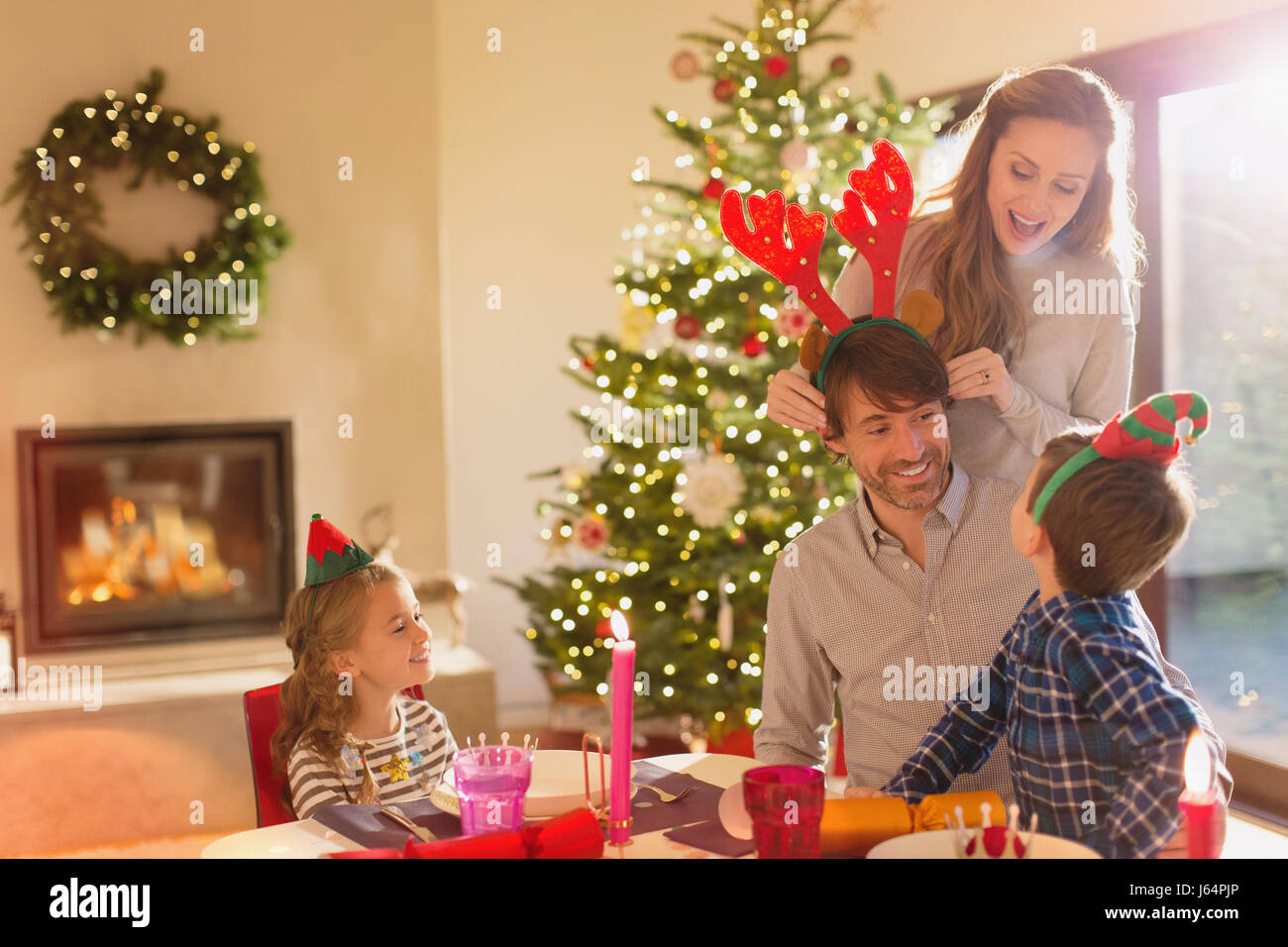 Family wearing elf and costume reindeer antlers at Christmas dining ...