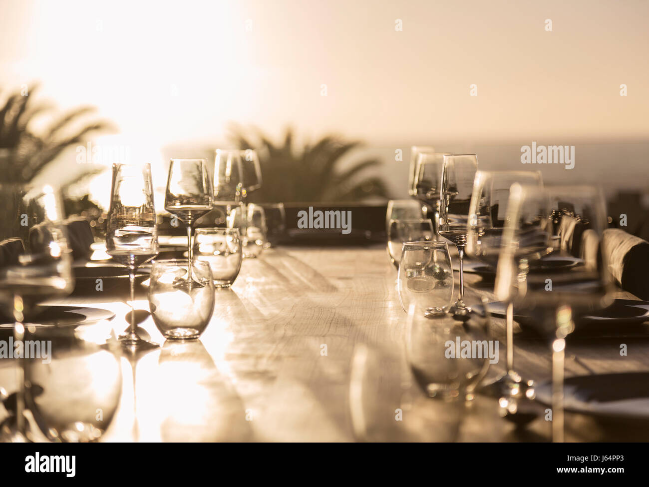 Glasses on sunny sunset patio table Stock Photo - Alamy