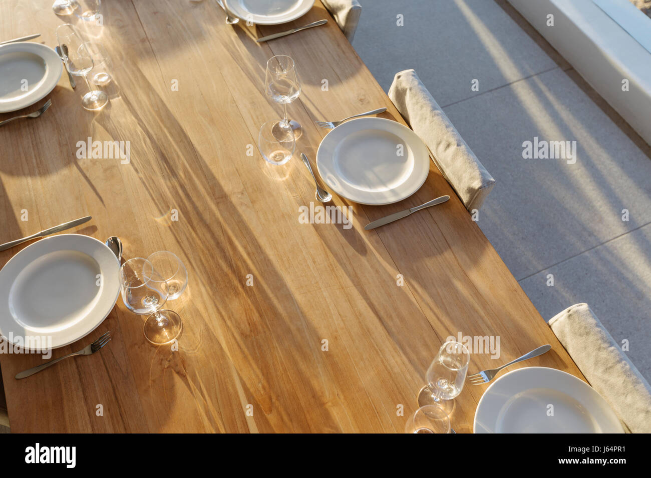 Placesettings on sunny wooden patio table Stock Photo - Alamy
