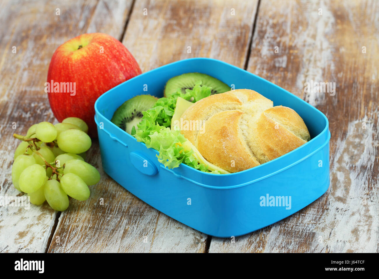 School lunch box containing cheese sandwich fresh fruit: kiwi, apple ...