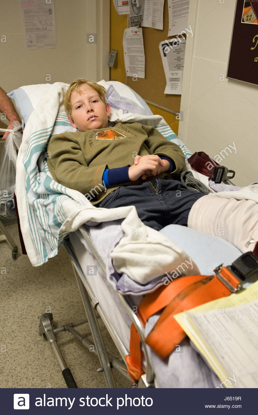 Eleven year old boy with a broken leg lying on hospital gurney before ...