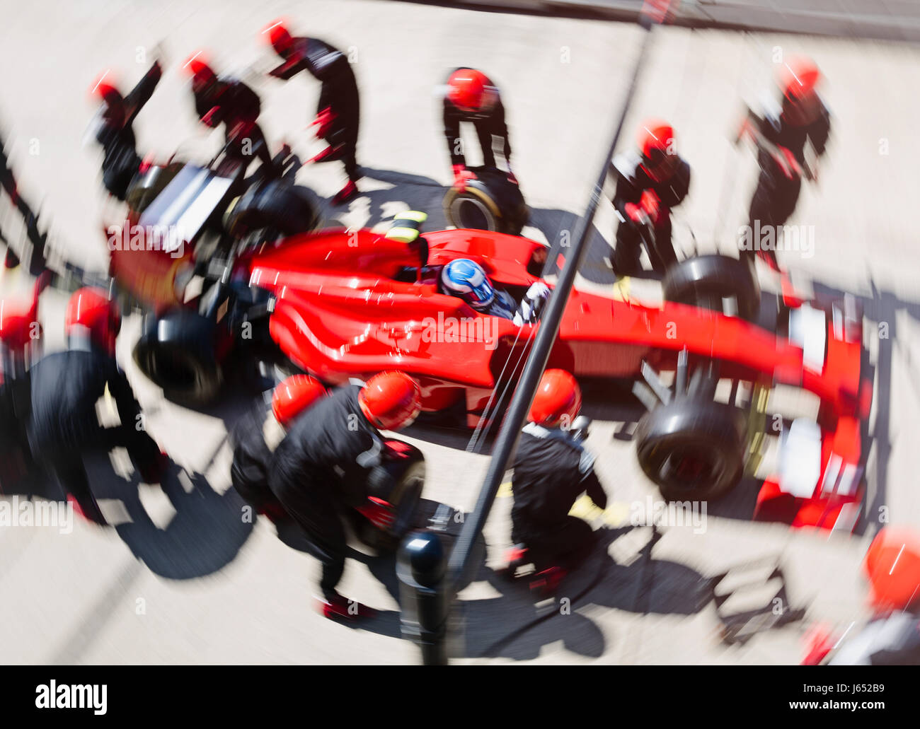 Overhead pit crew replacing tires on formula one race car in pit lane ...