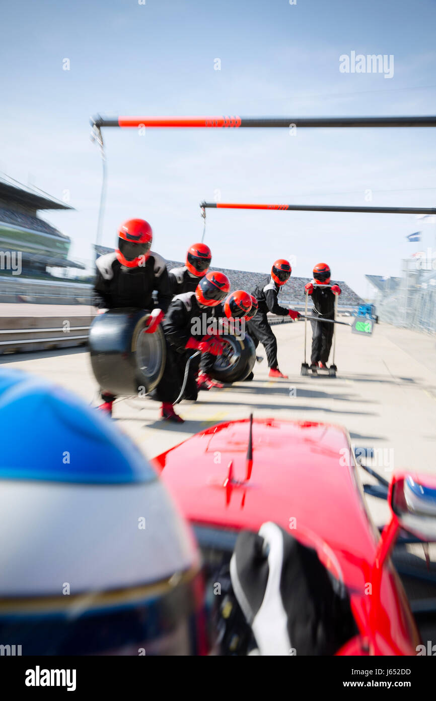 Pit crew with tires ready for nearing formula one race car in pit lane ...