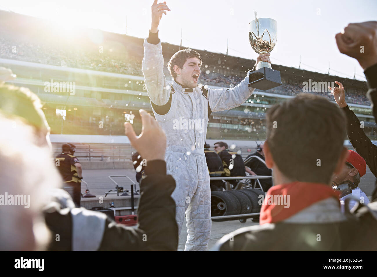 Formula one racing team cheering for driver with trophy, celebrating ...