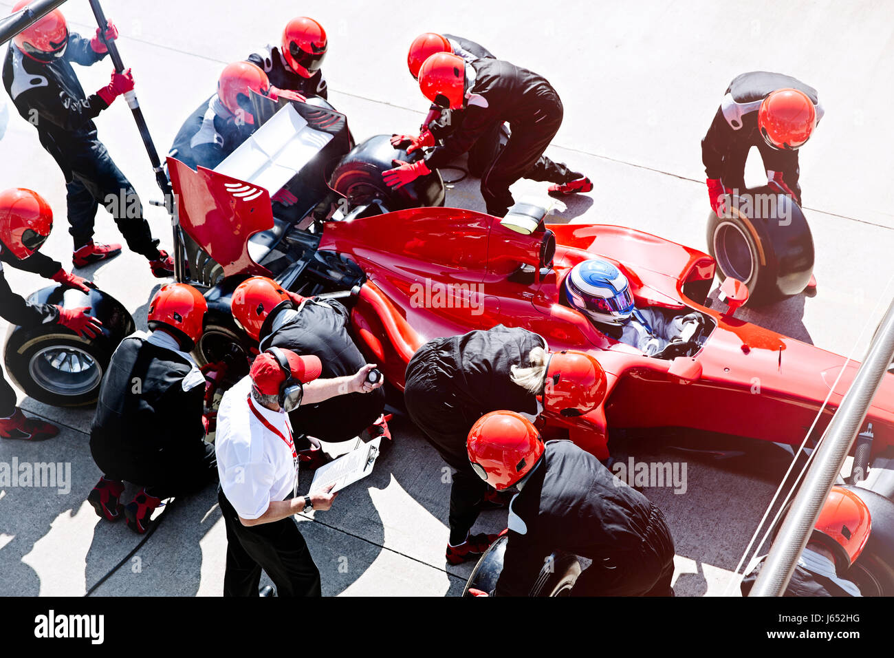 Manager with stopwatch timing pit crew replacing tires in pit lane ...