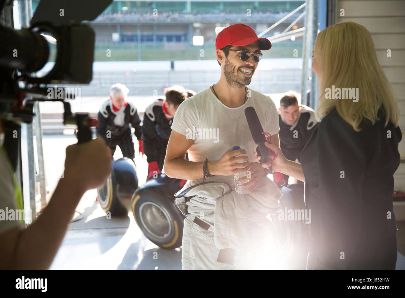 Female news reporter interviewing male formula one race car driver in ...