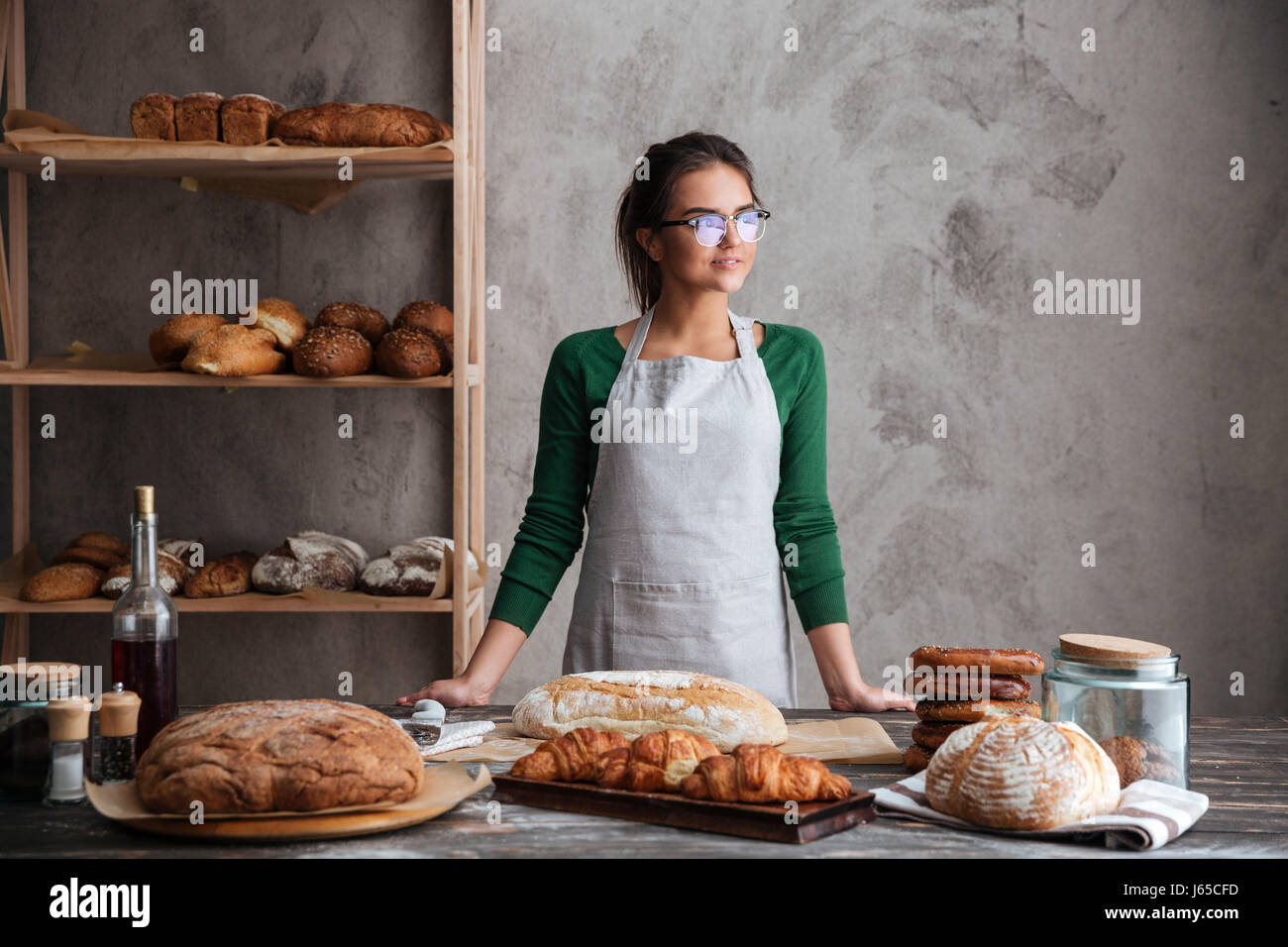 Picture of amazing young lady baker standing at bakery near bread ...