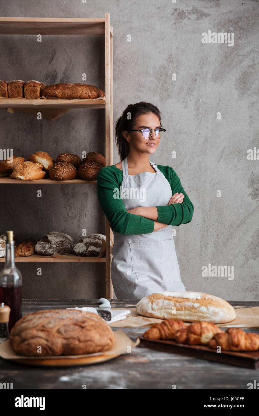 Picture of concentrated young lady baker standing with arms crossed at ...