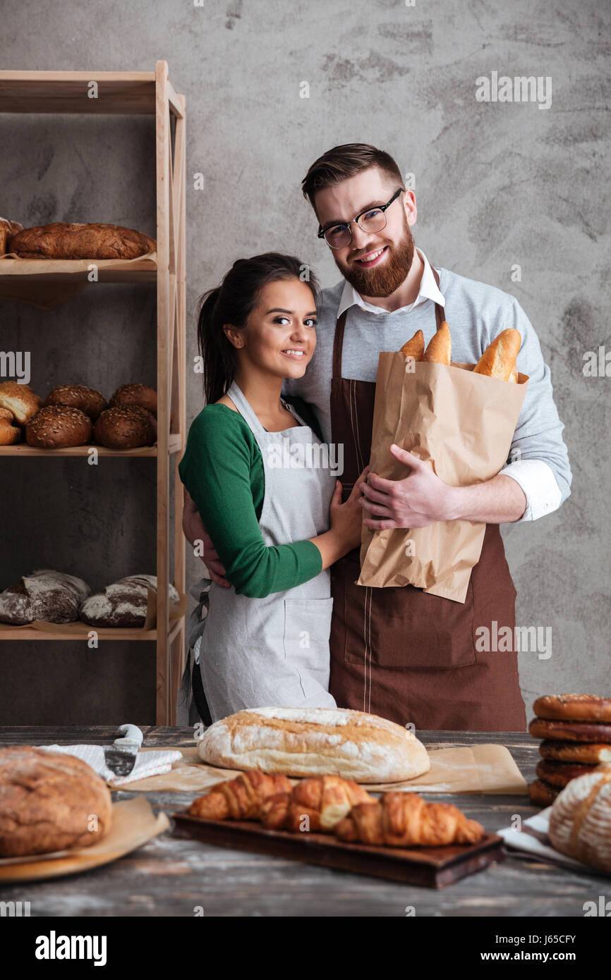 Vertical image of bakers which hugging in bakery and looking at the ...