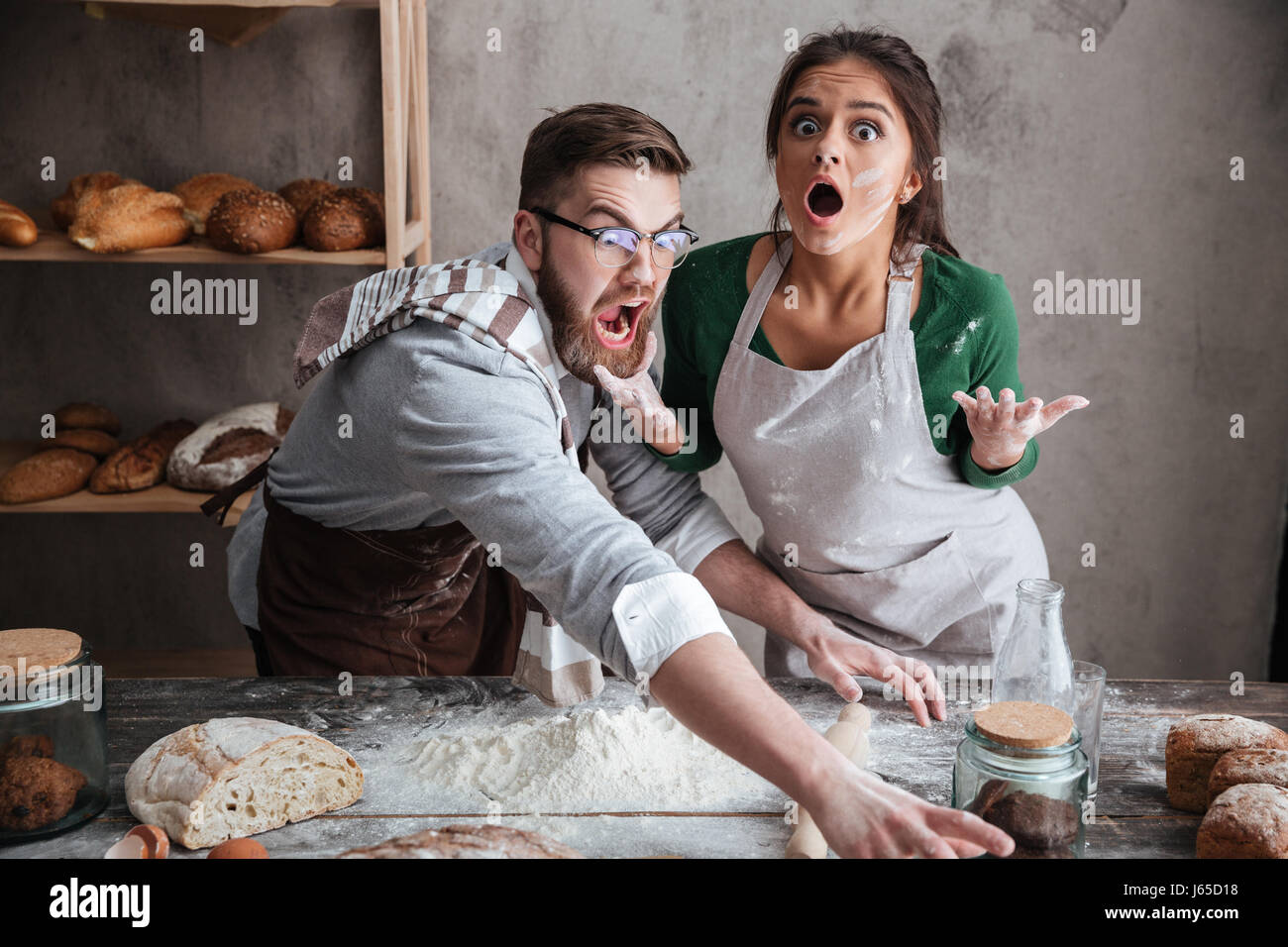 Shocked man and suprised woman trying to catch something on table with ...