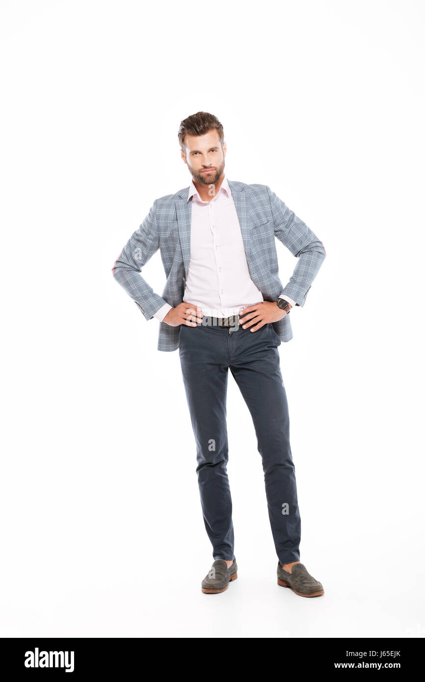 Photo of serious young man standing isolated over white background ...