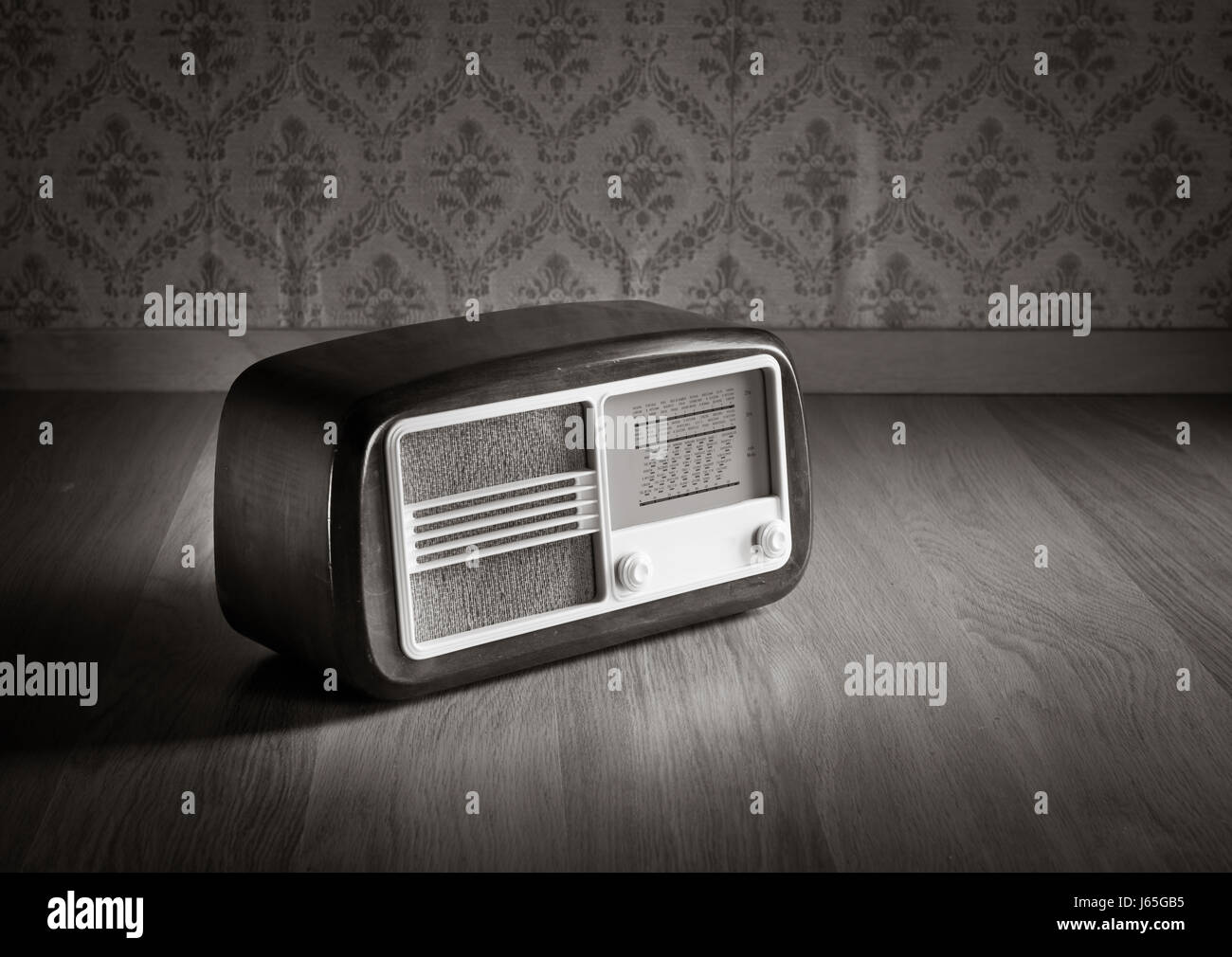 Old vintage radio on hardwood floor with retro wallpaper on background ...