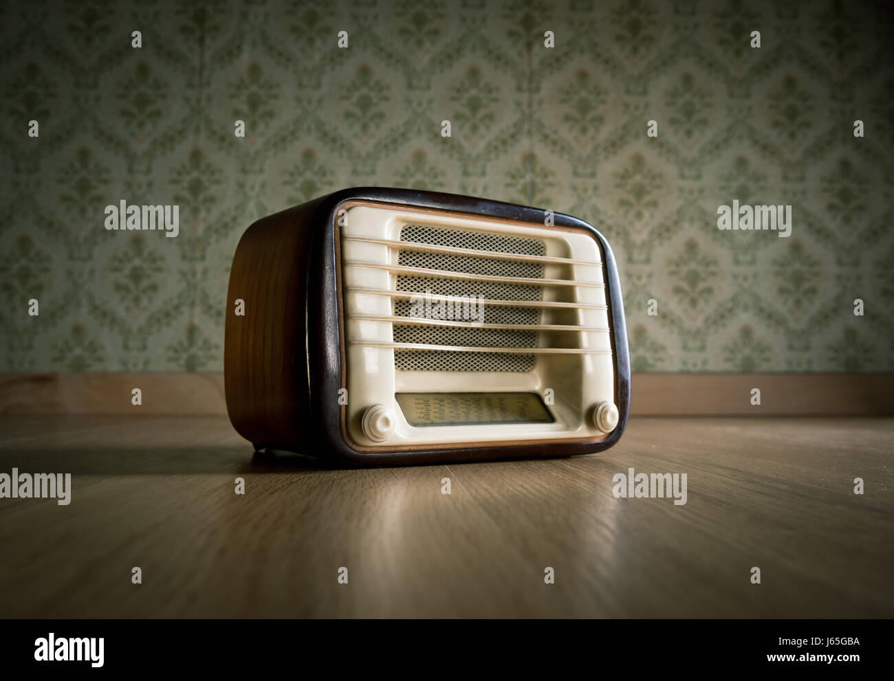 Old vintage radio on hardwood floor with retro wallpaper on background ...