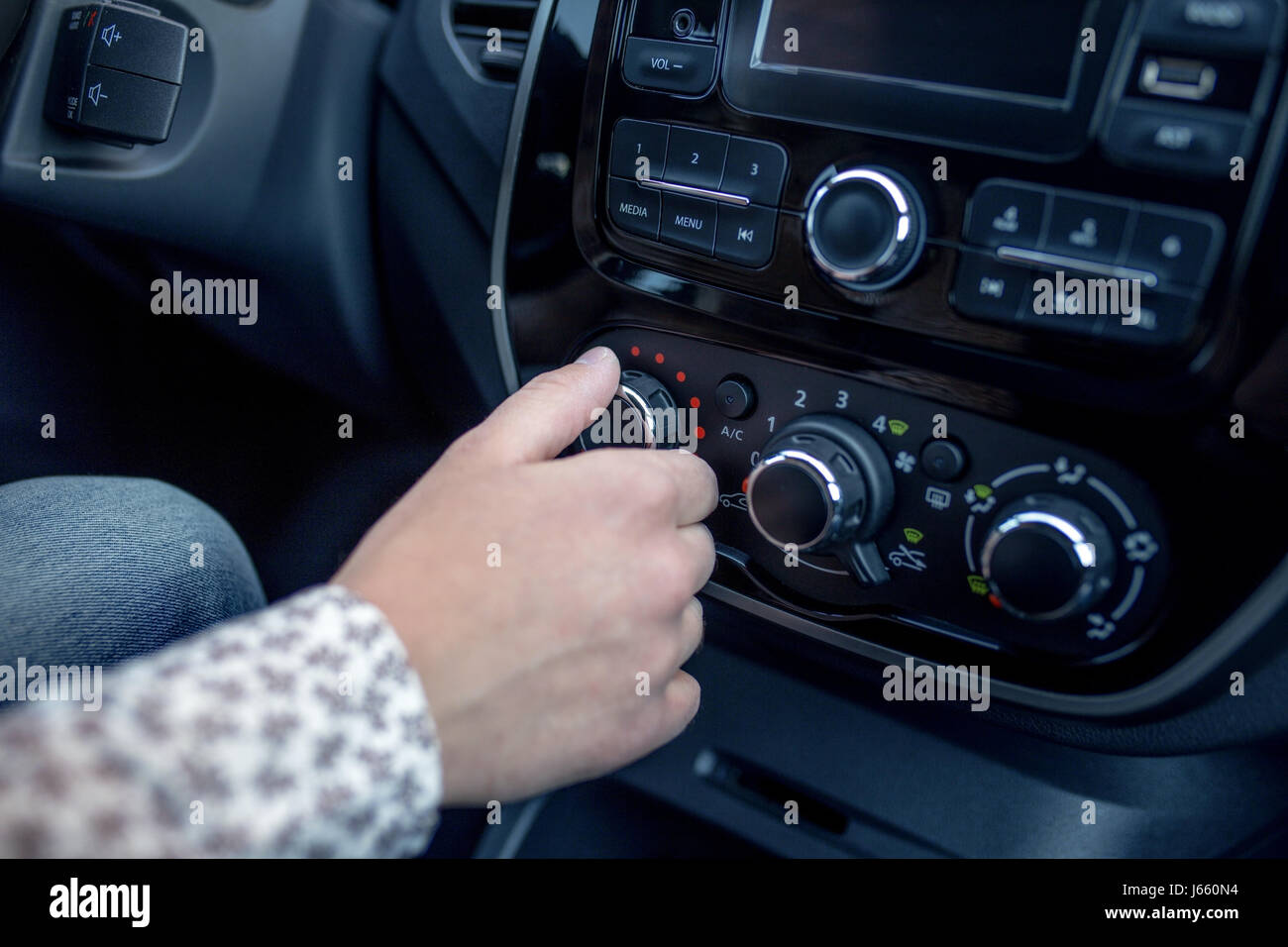 male hand pressing button in modern car. Man adjusts the temperature of ...