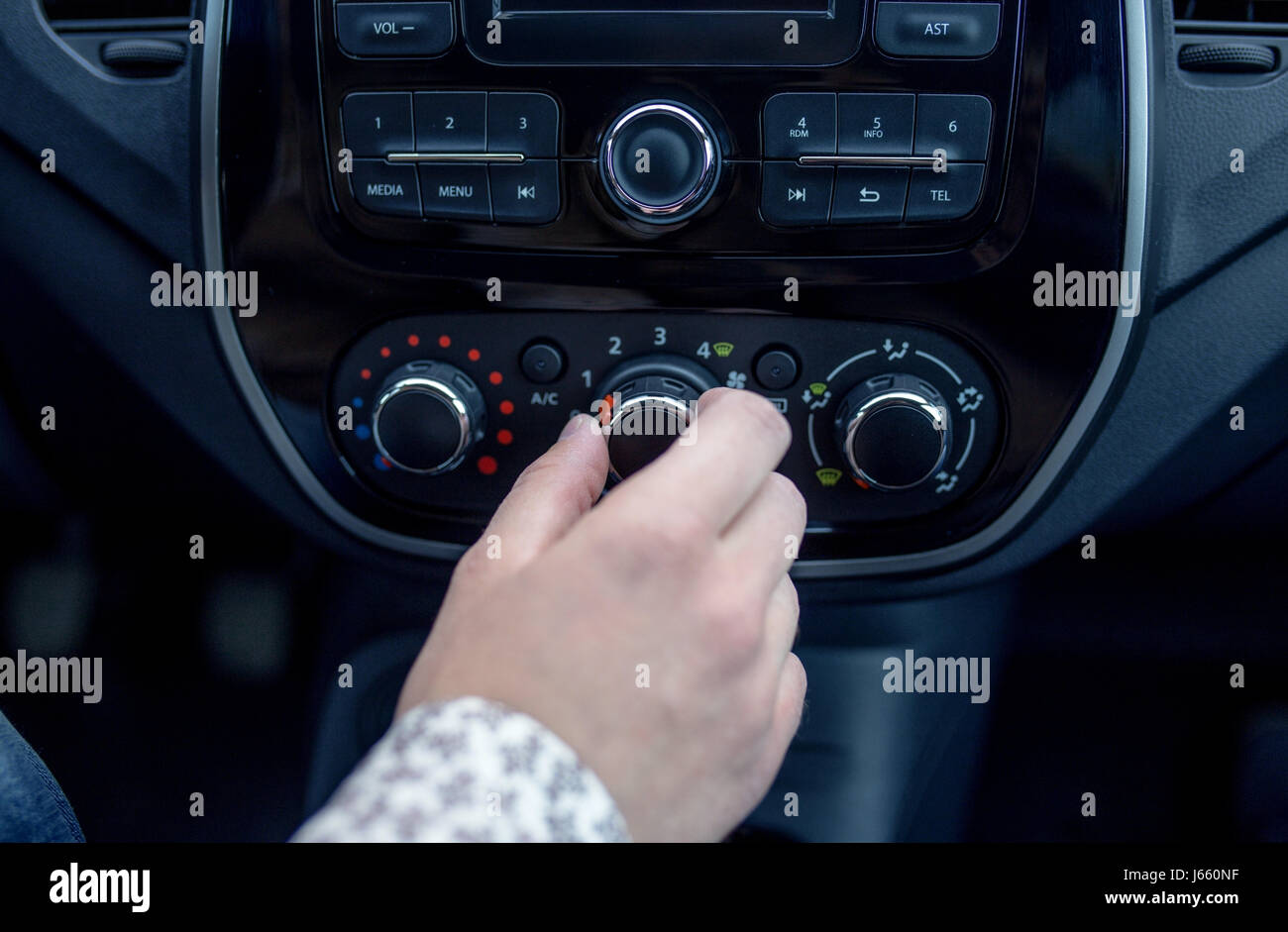 male hand pressing button in modern car. Man adjusts the temperature of ...