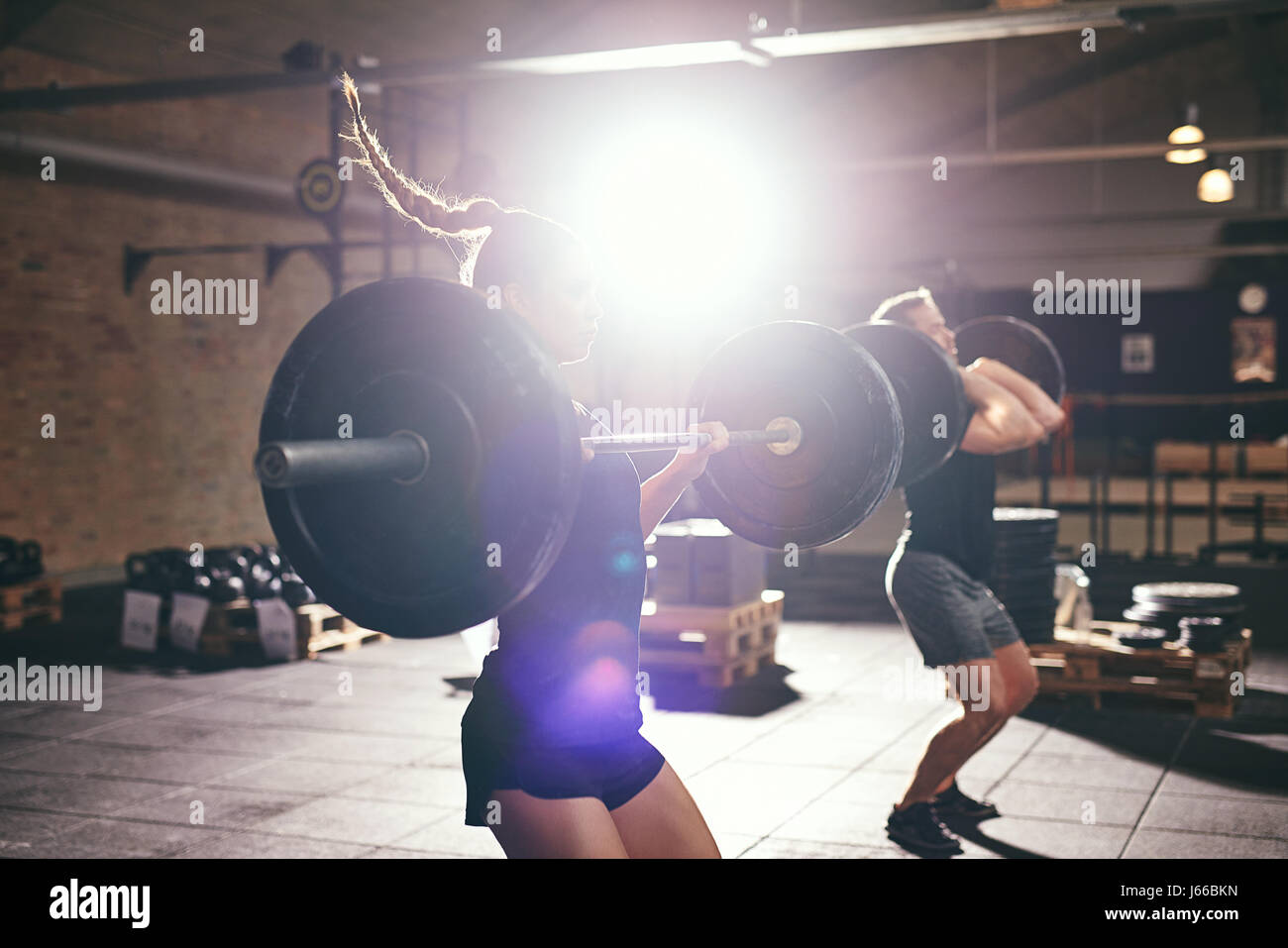 Side view of young man and woman lifting barbells in gym Stock Photo ...
