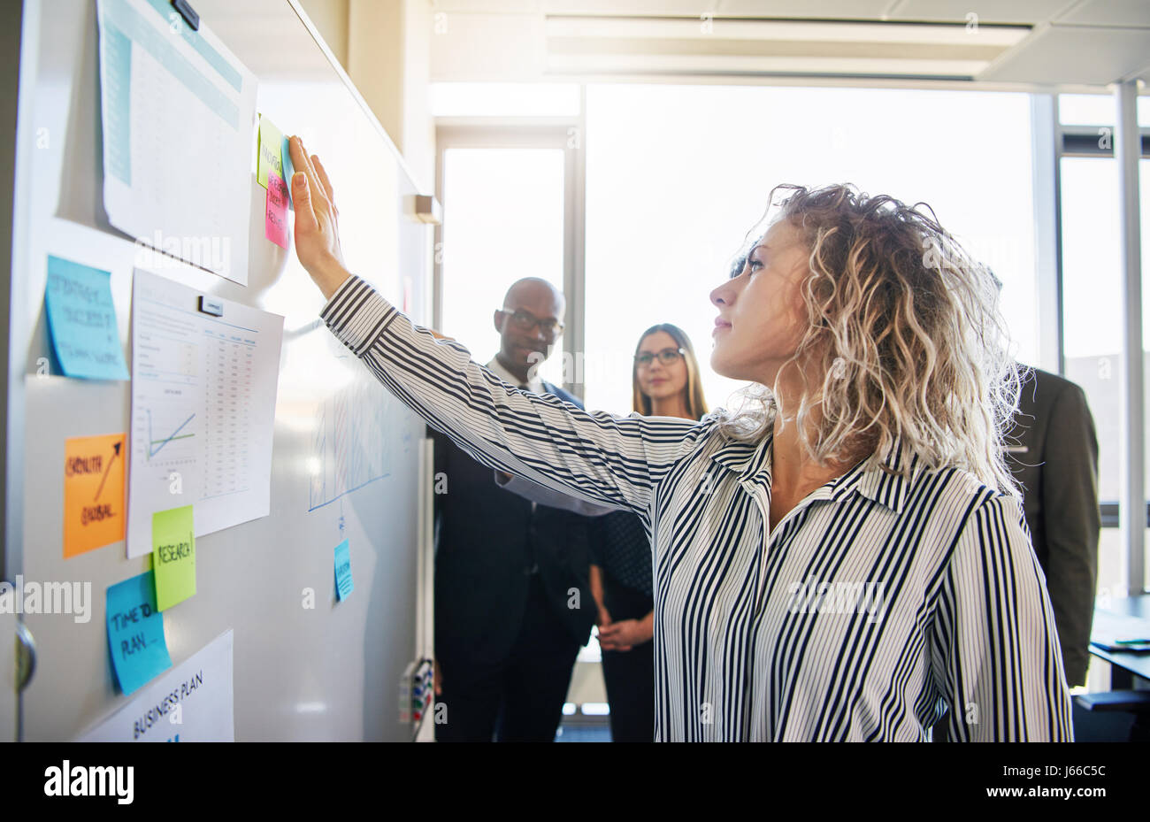 Diverse business team brainstorming in office looking at whiteboard ...