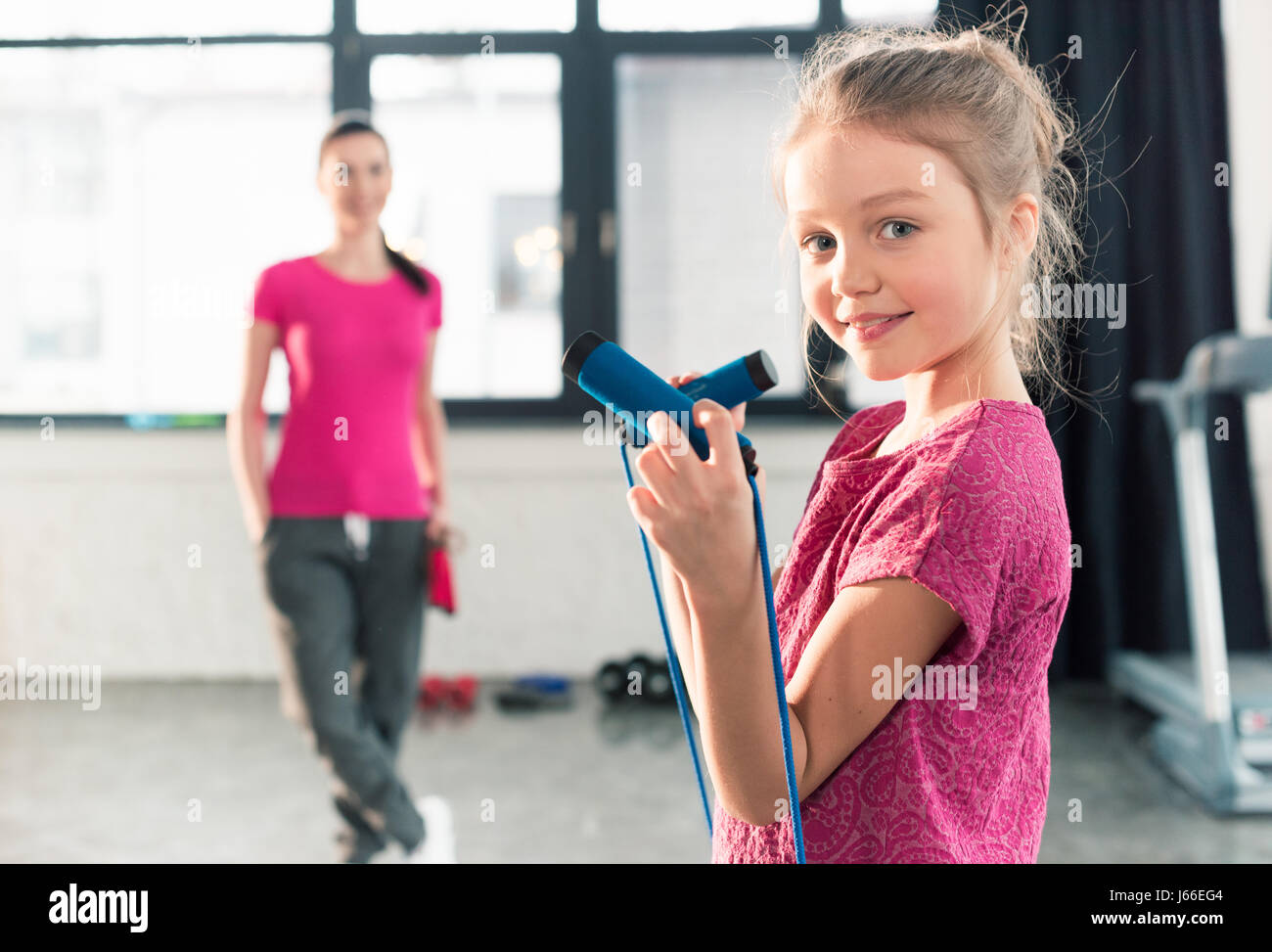 Mother looking at cute little daughter holding skipping rope and ...