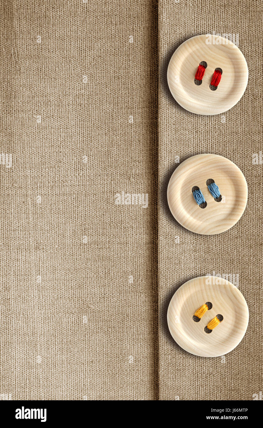 Three wooden button with colored threads on canvas background Stock ...