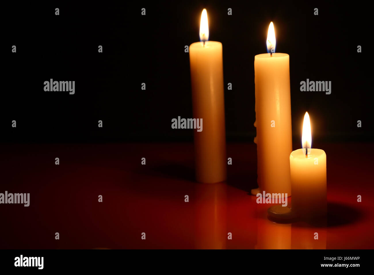 Three lighting candles on dark background with reflection Stock Photo ...