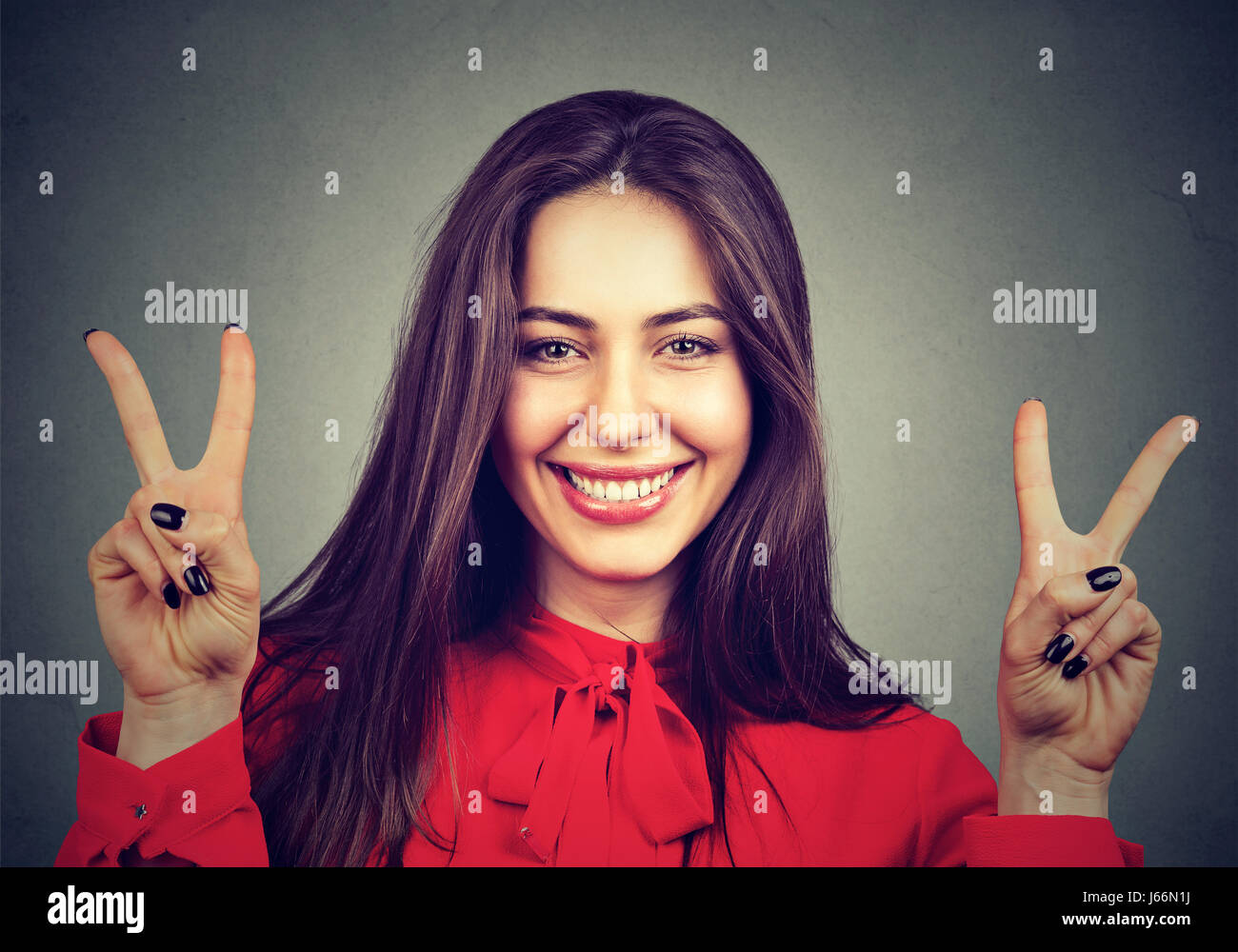 Smiling woman showing peace hand sign with both hands Stock Photo - Alamy