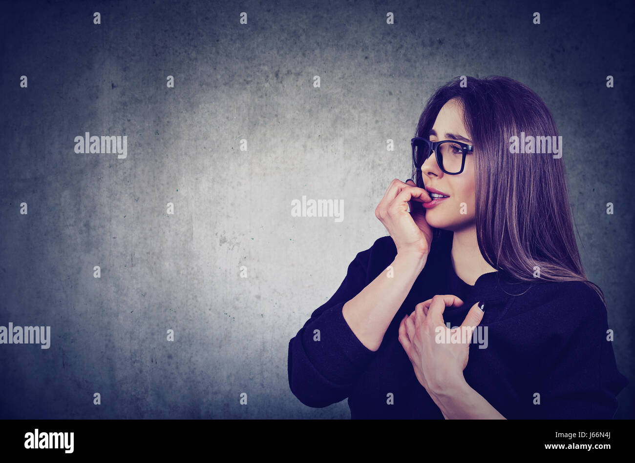 Side profile hesitant anxious woman biting her fingernails looking ...