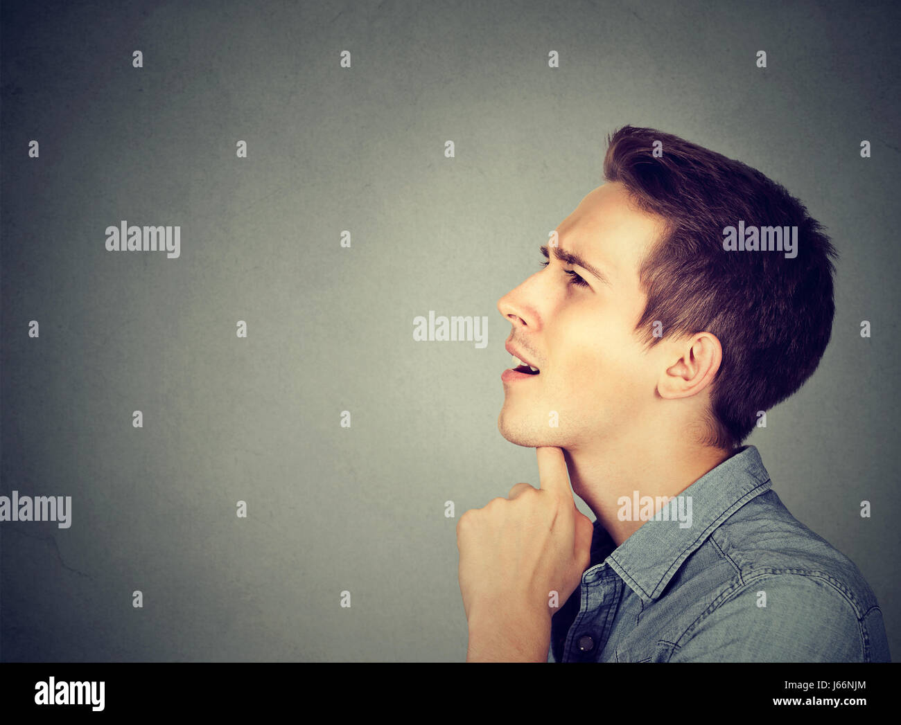 Thoughtful young man standing by the wall Stock Photo - Alamy