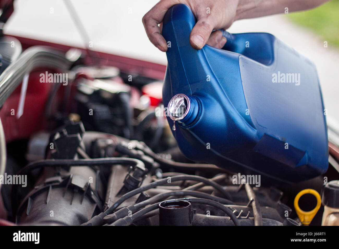 Raised the hood of the car, the master pours oil in the engine of the ...