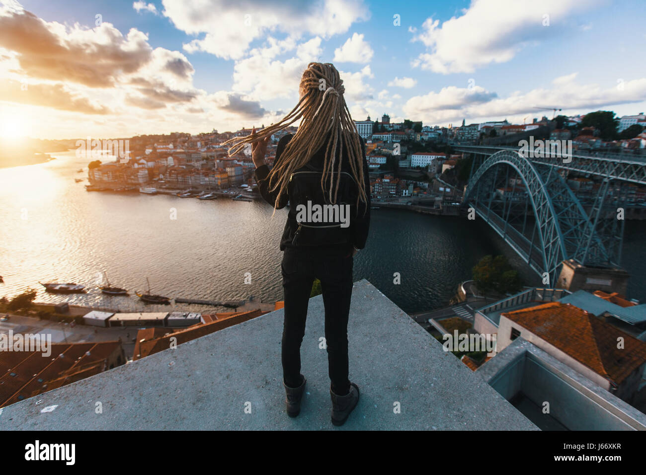 Girl with blonde dreadlocks standing on the background of the bridge ...