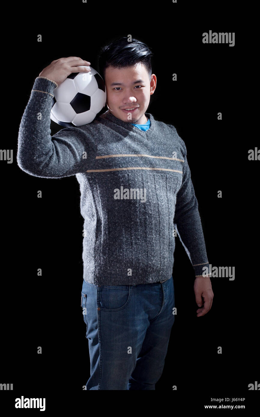 young man holding soccer football with smiling face standing against ...