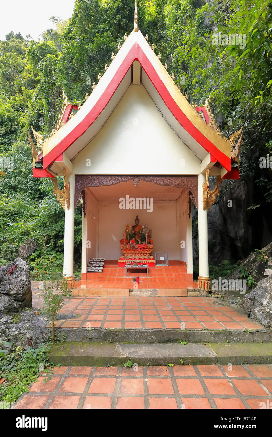 Small Buddhist shrine-gilded Buddha statue on altar at the foot of the ...