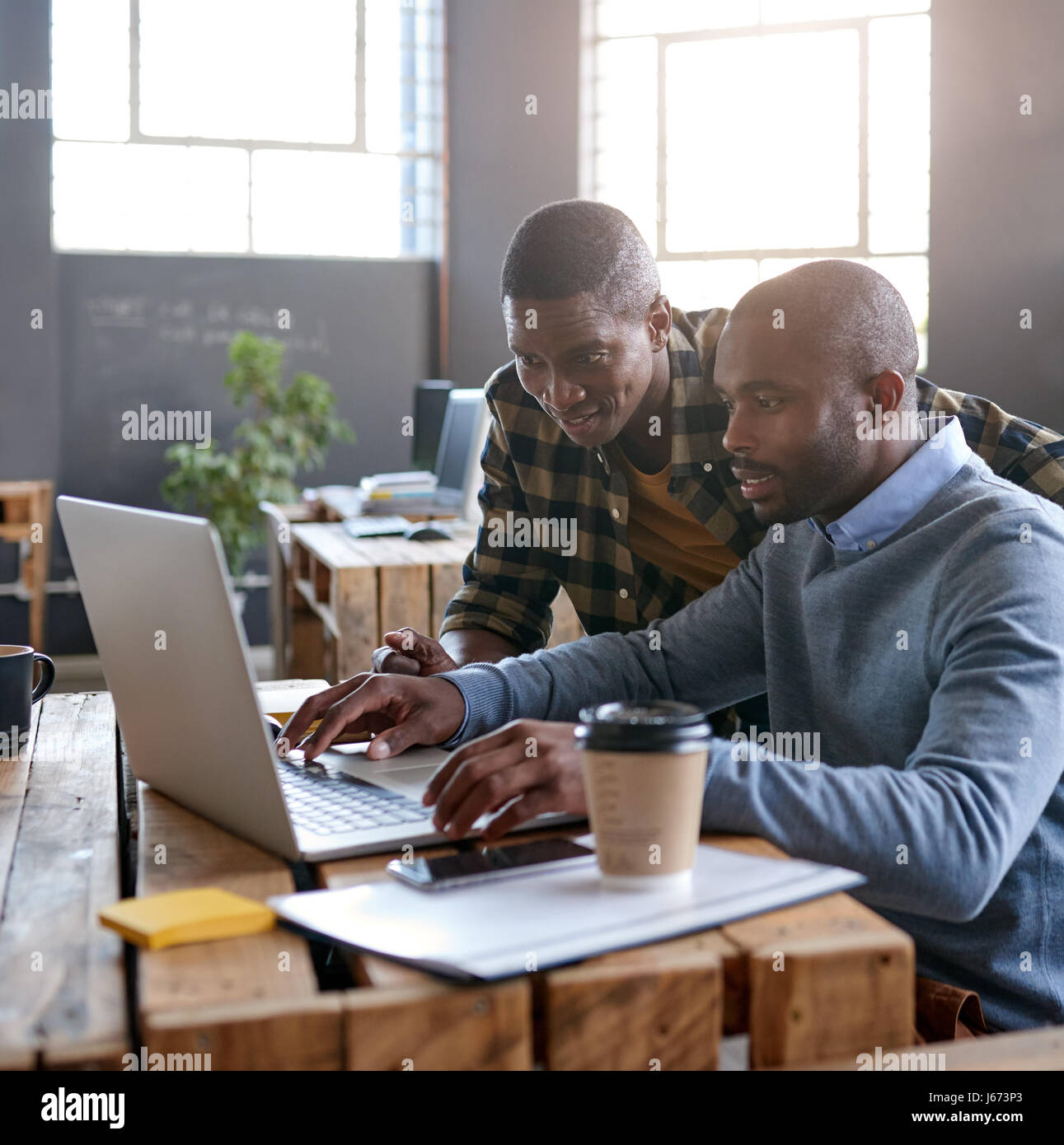 Smiling African colleagues using a laptop together in an office Stock ...