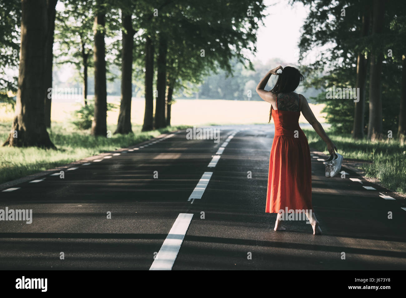 Woman in red dress walking on road Stock Photo - Alamy