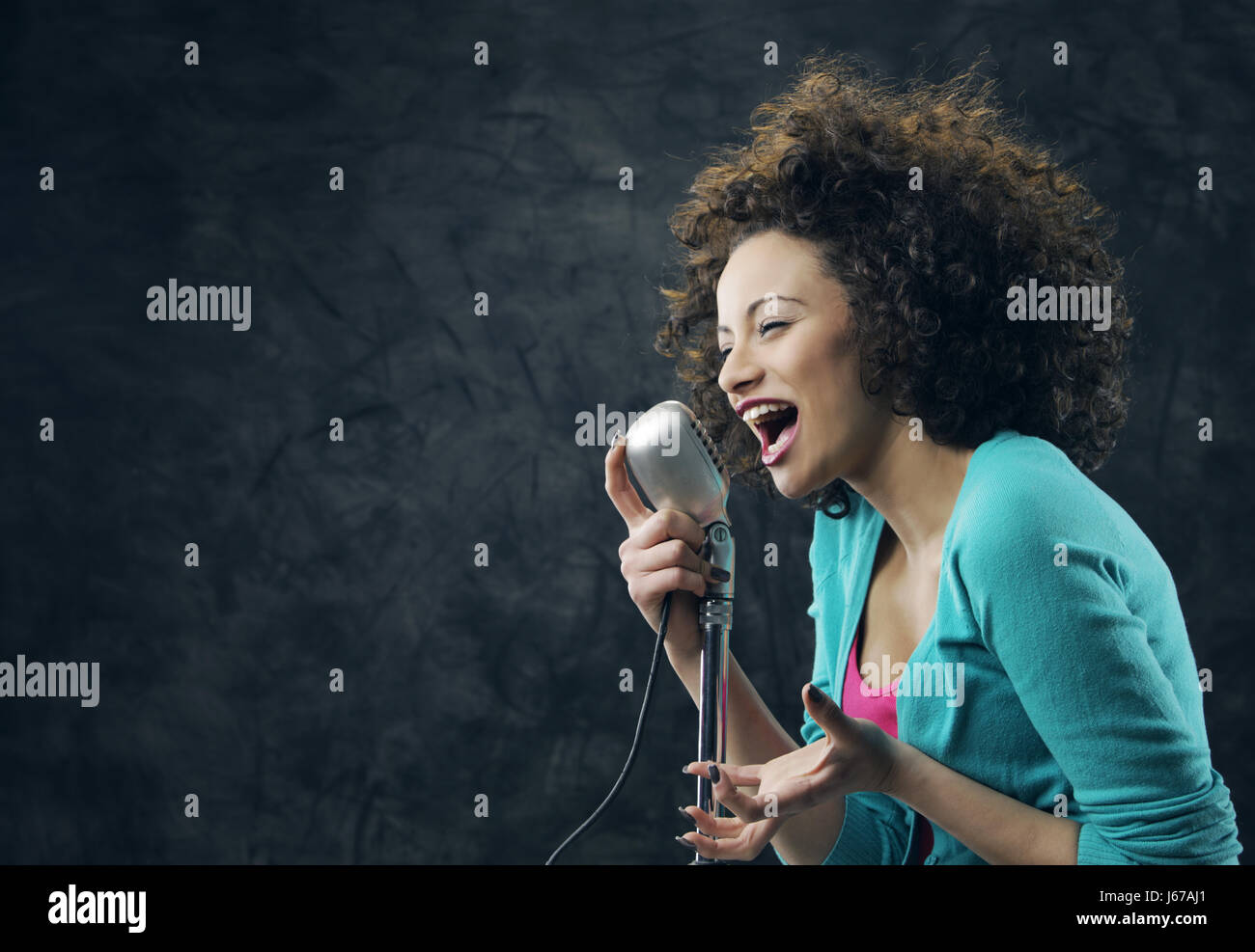 Young female singer with brown curly hair singing a song Stock Photo ...