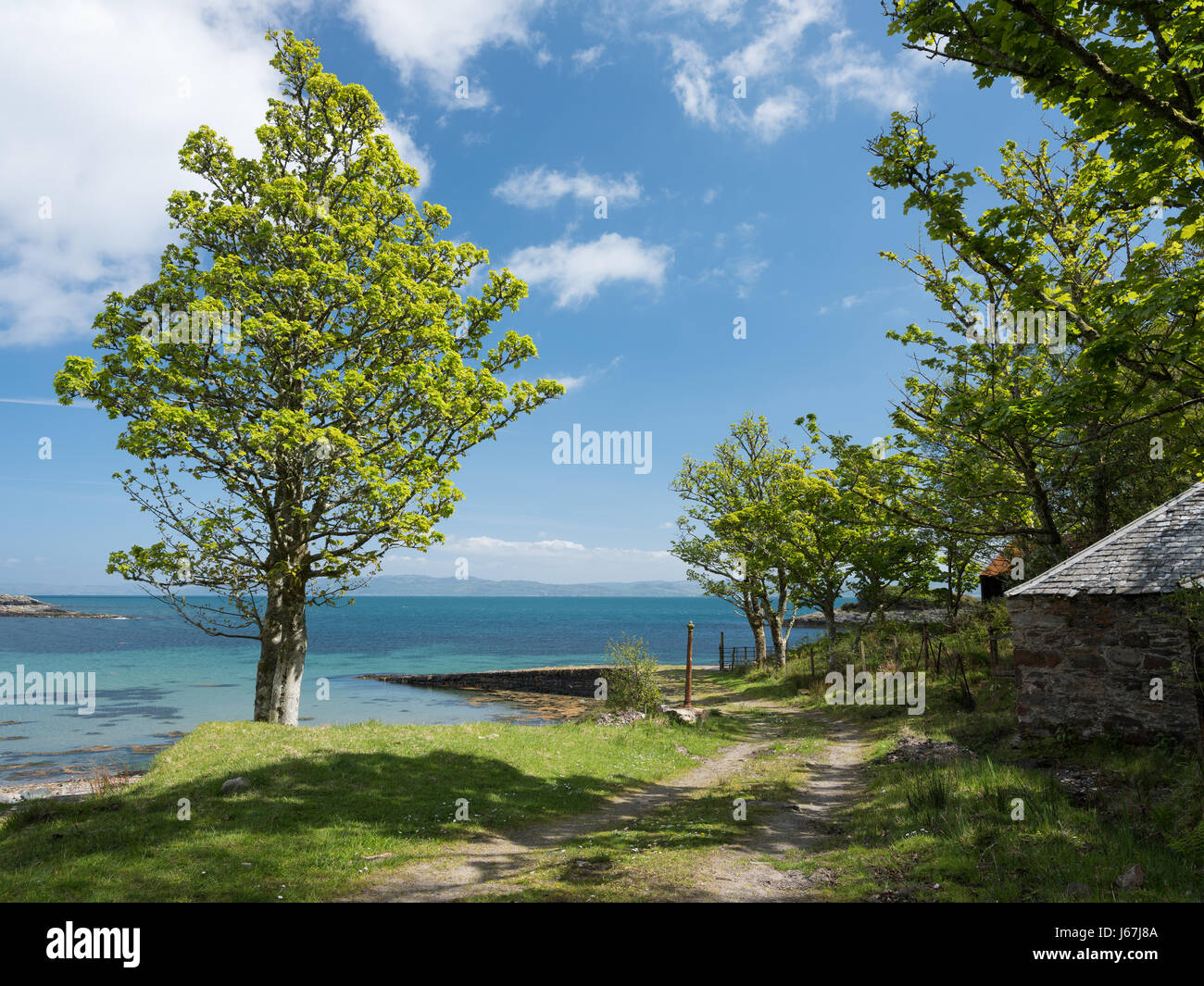 Ardlussa Bay on Scottish Island of Jura showing jetty and sheds. Bright ...