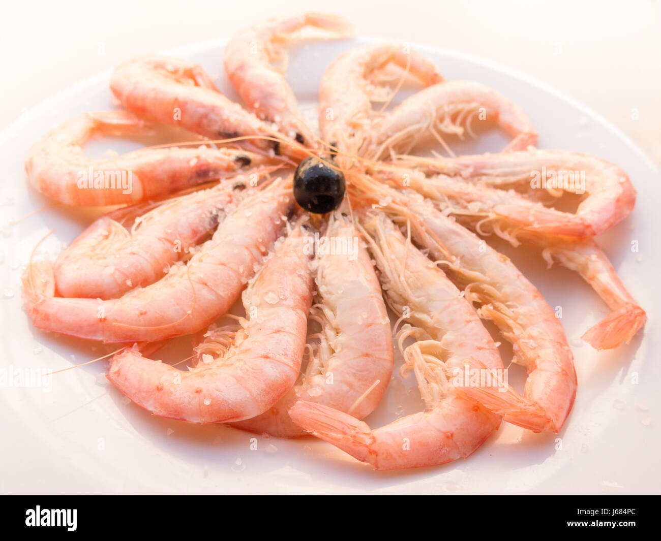 cooked pink prawns in their shells displayed in a spiral on a white ...
