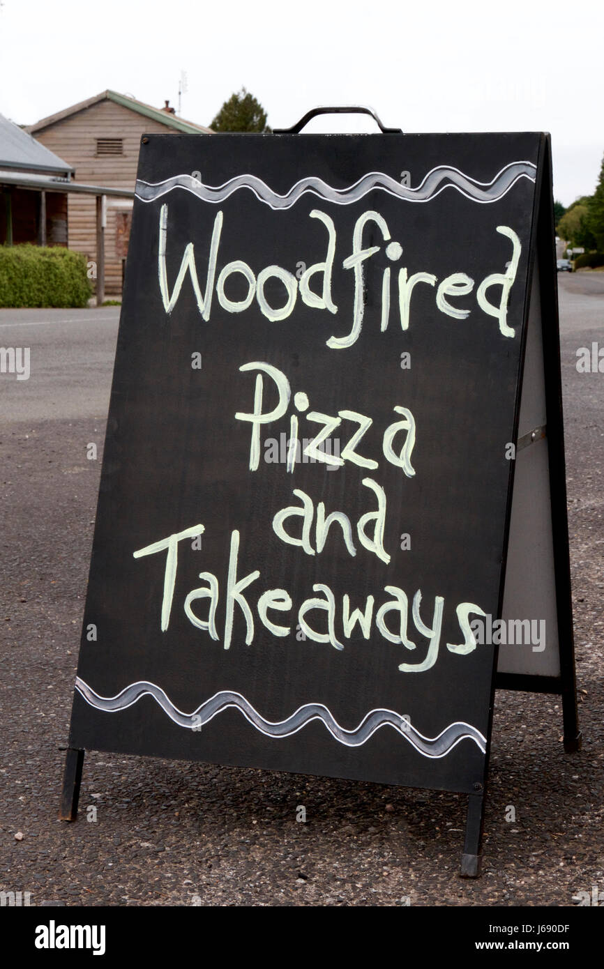 Woodfired pizza sign beside road Stock Photo - Alamy
