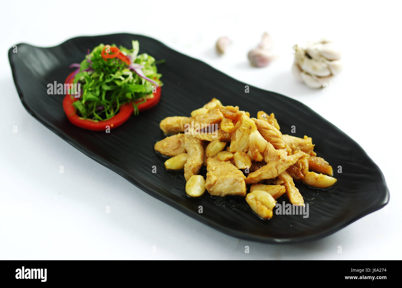 Grilled boneless chicken with garlic and salad on black platter Stock ...