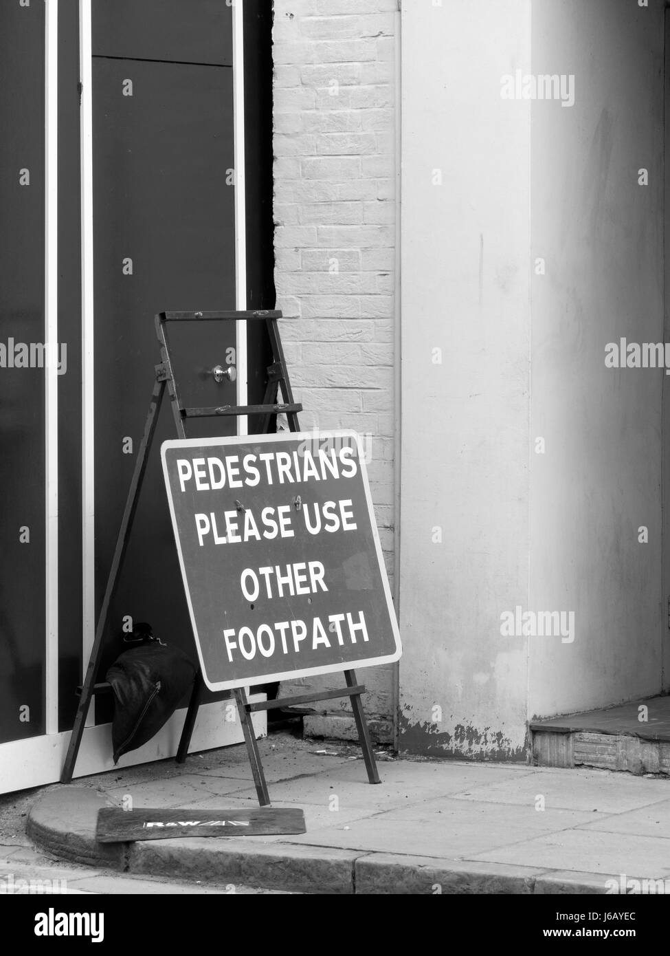 Pedestrians use other footpath sign due to construction site hoarding ...