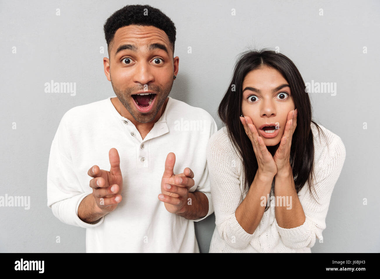 Photo of young shocked loving couple posing over grey wall and looking ...