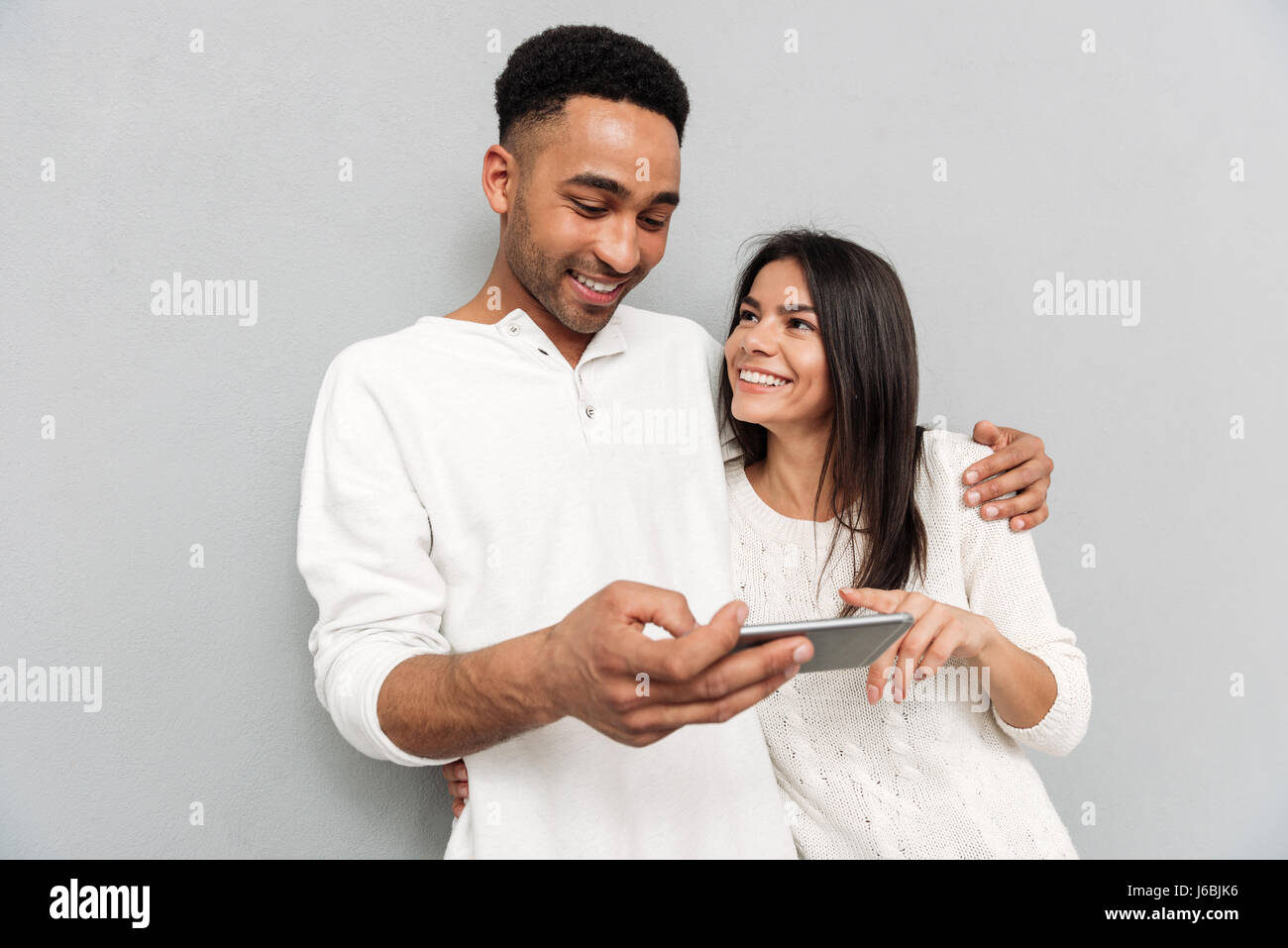 Pretty couple hugging and using smartphone isolated Stock Photo - Alamy