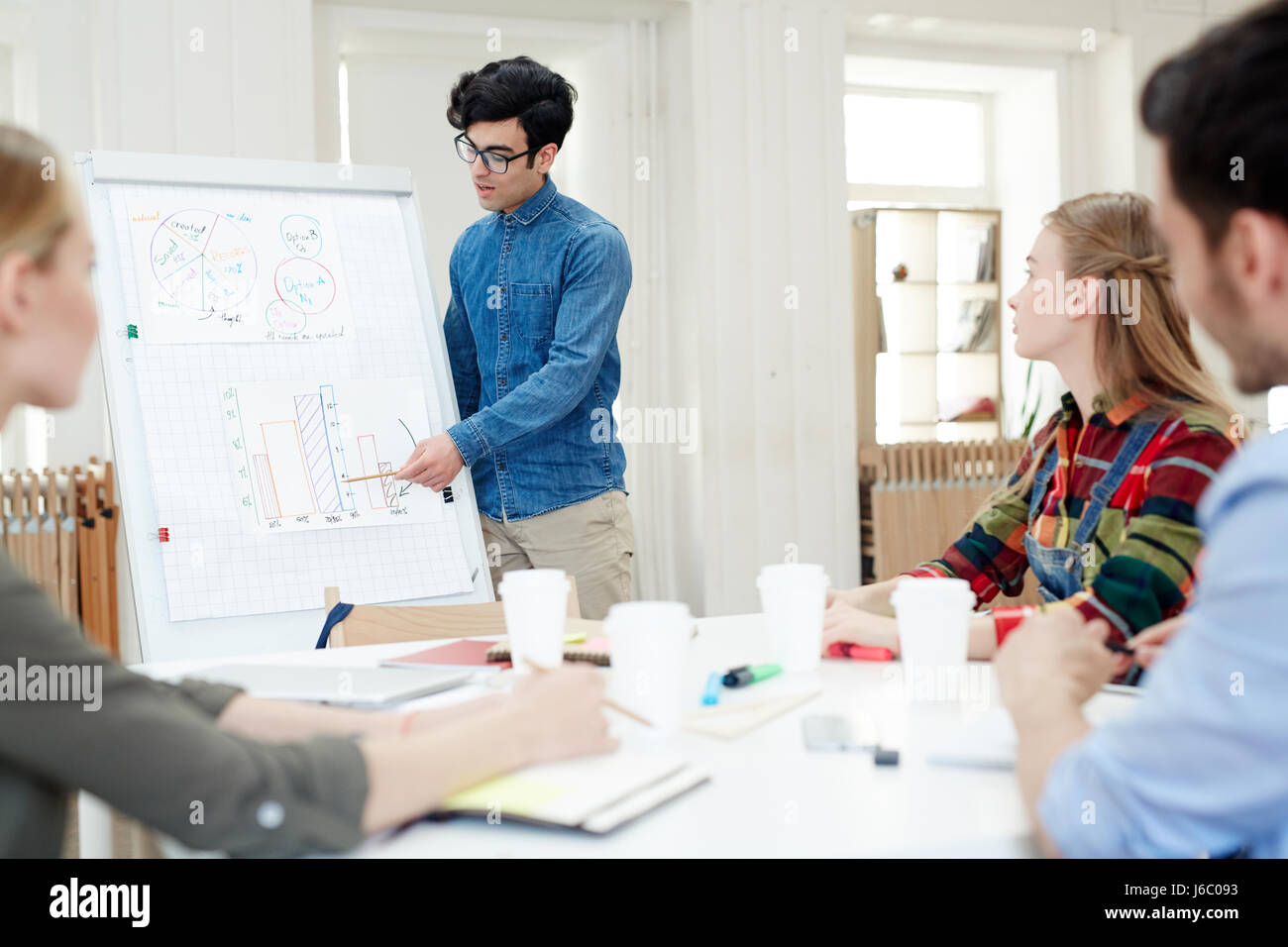 Clever student explaining charts and diagrams to groupmates Stock Photo ...
