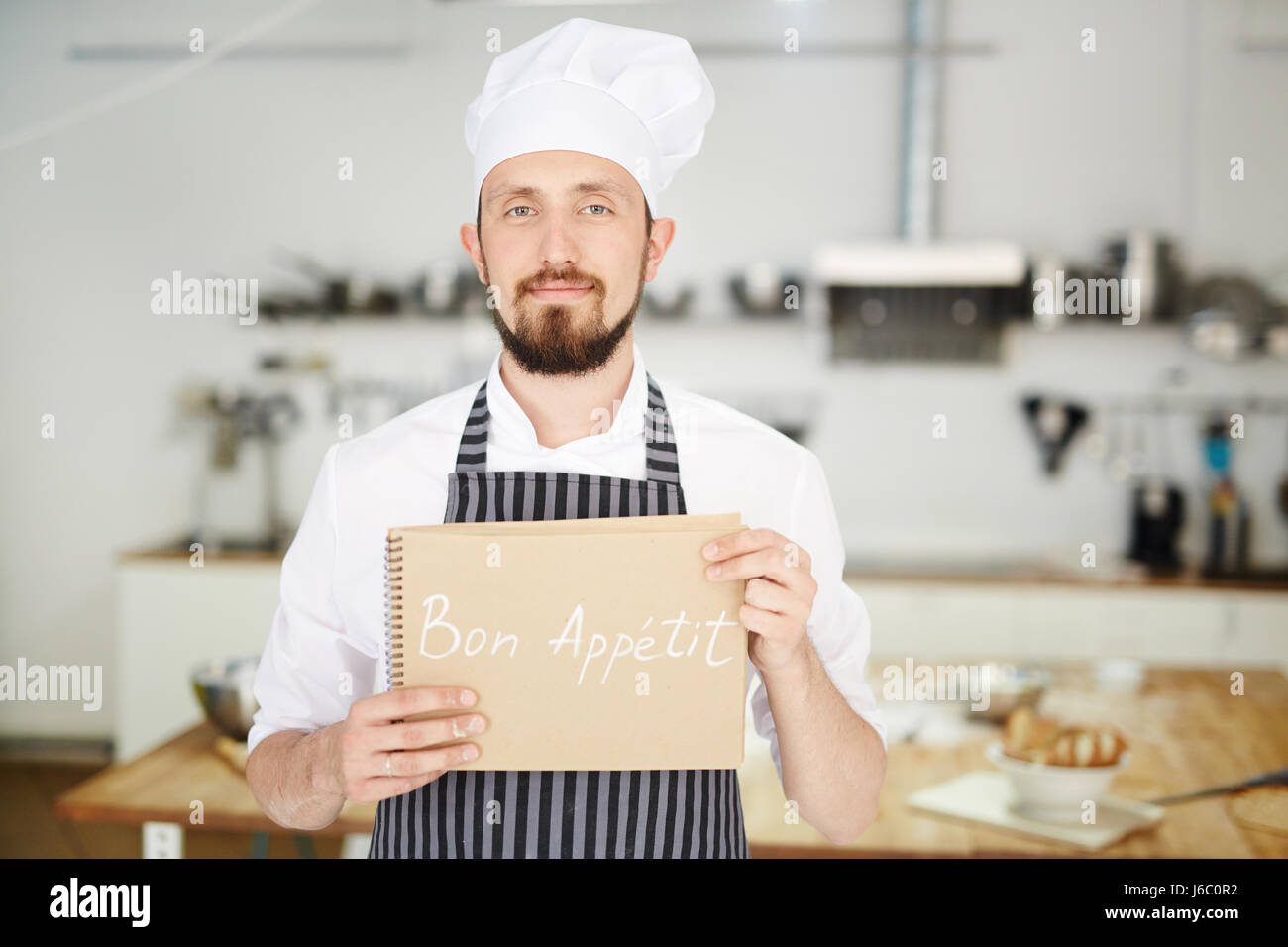 Professional baker holding notepad with wish of good appetite Stock ...