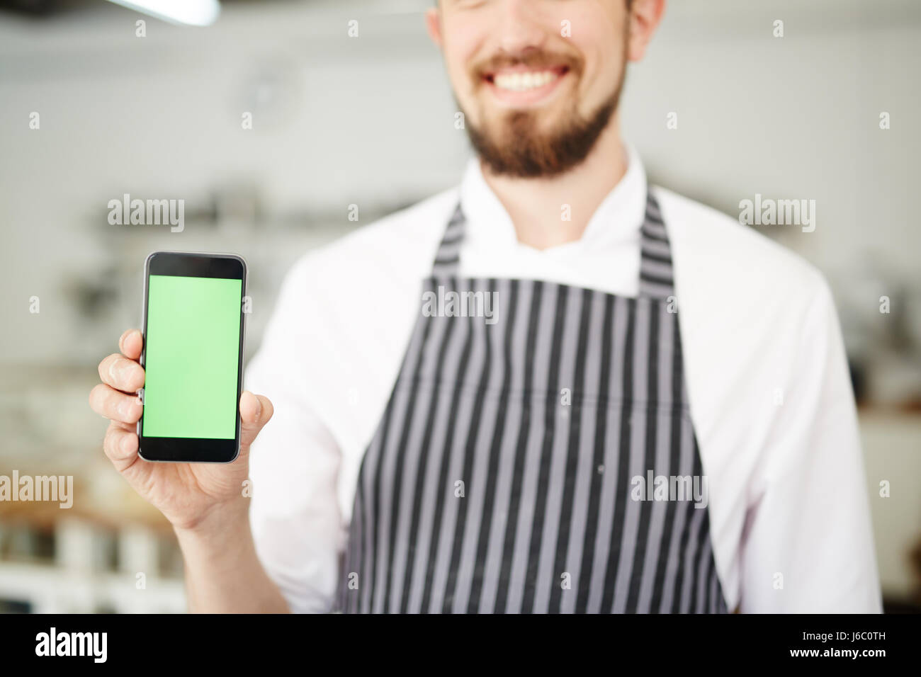 Baker with smartphone showing online video class Stock Photo - Alamy