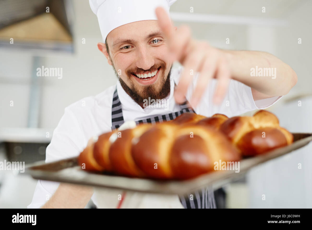 Smiling baker with fresh bread working in the kitchen Stock Photo - Alamy
